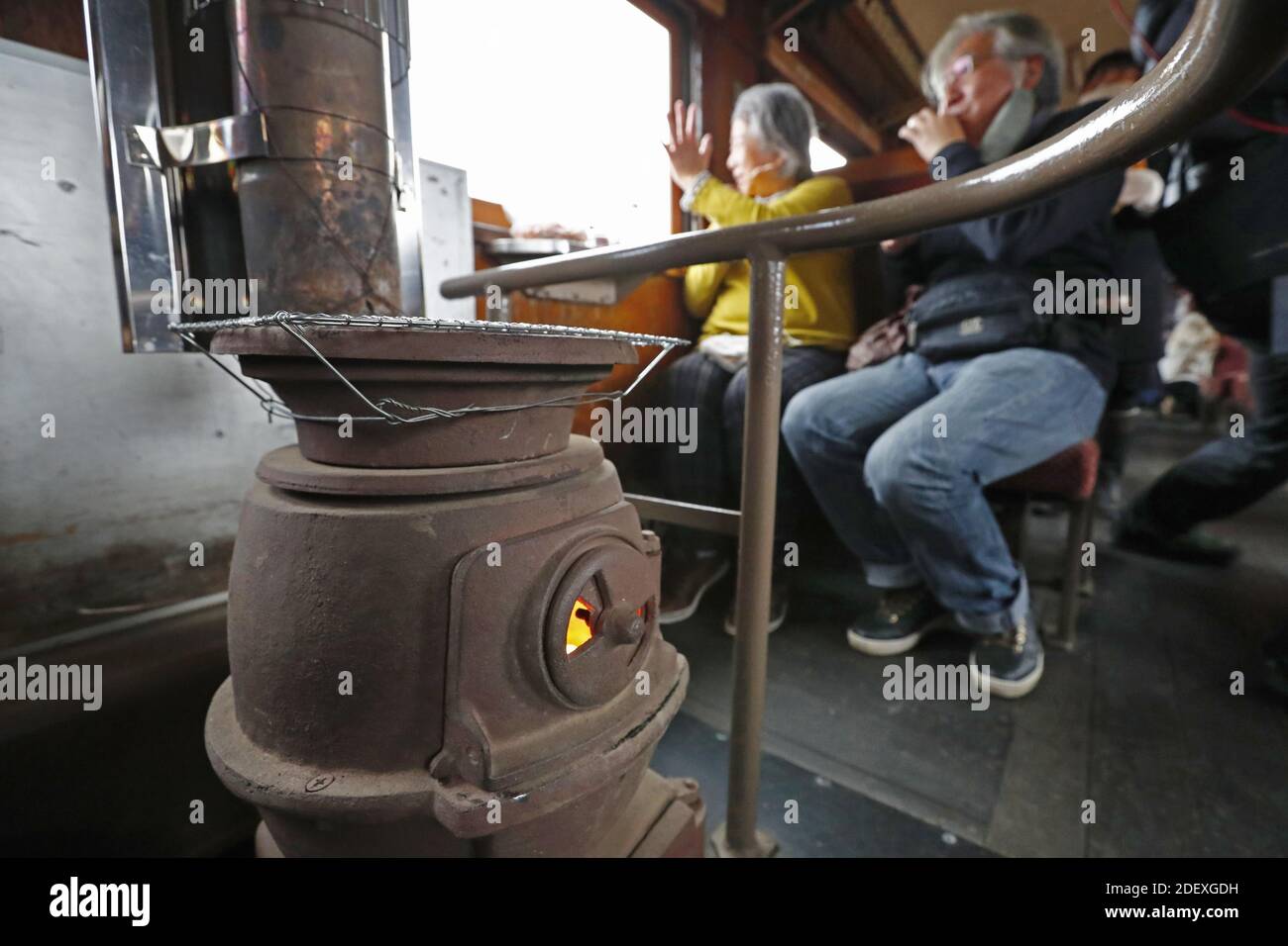 Passengers warm up by a coal stove on Tsugaru Railway's "stove train ...