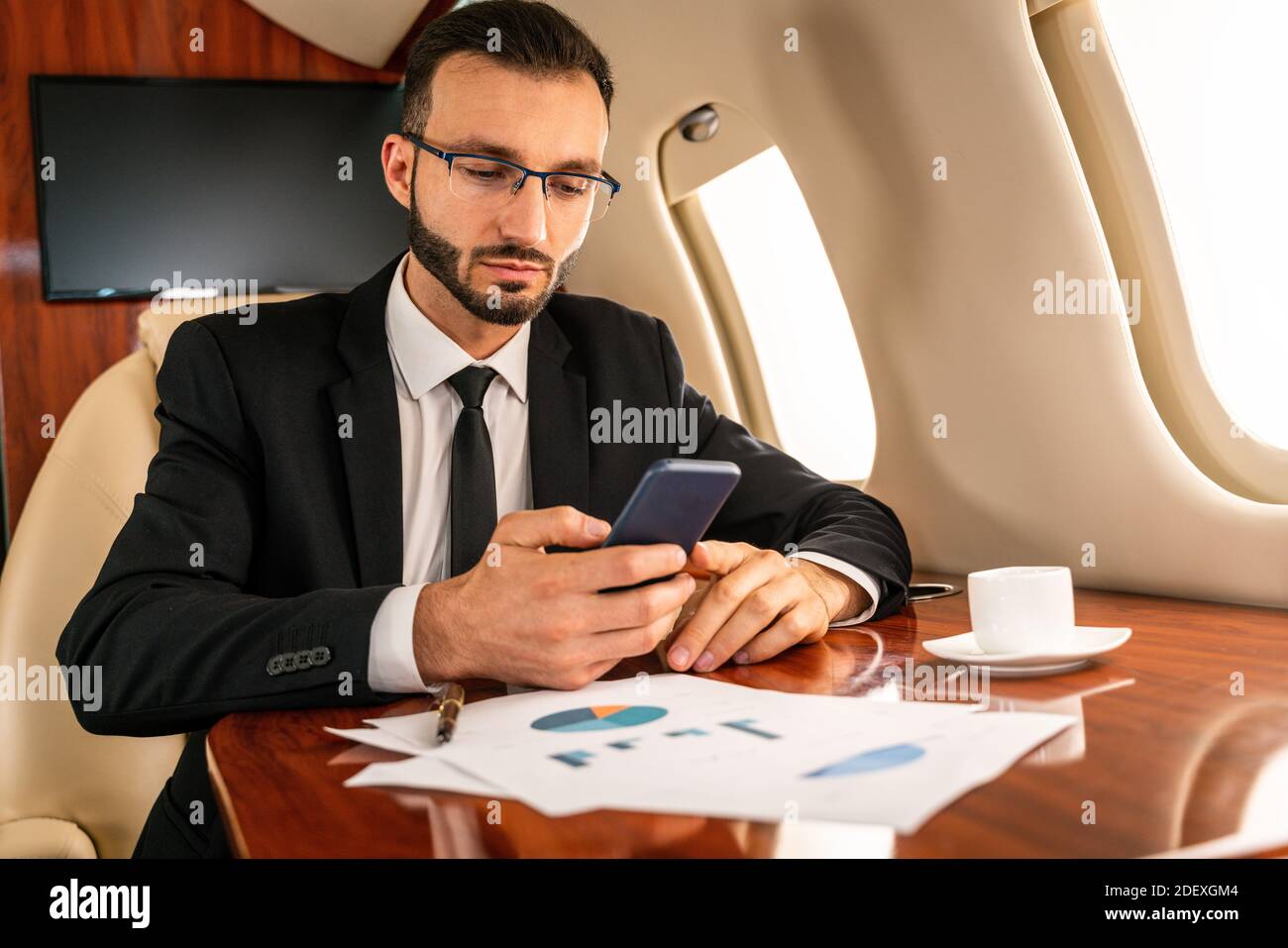 Handsome businessman wearing elegant suit flying on exclusive private ...