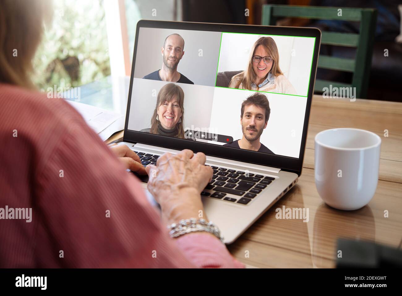 View over shoulder of senior woman talking by video call with a group ...