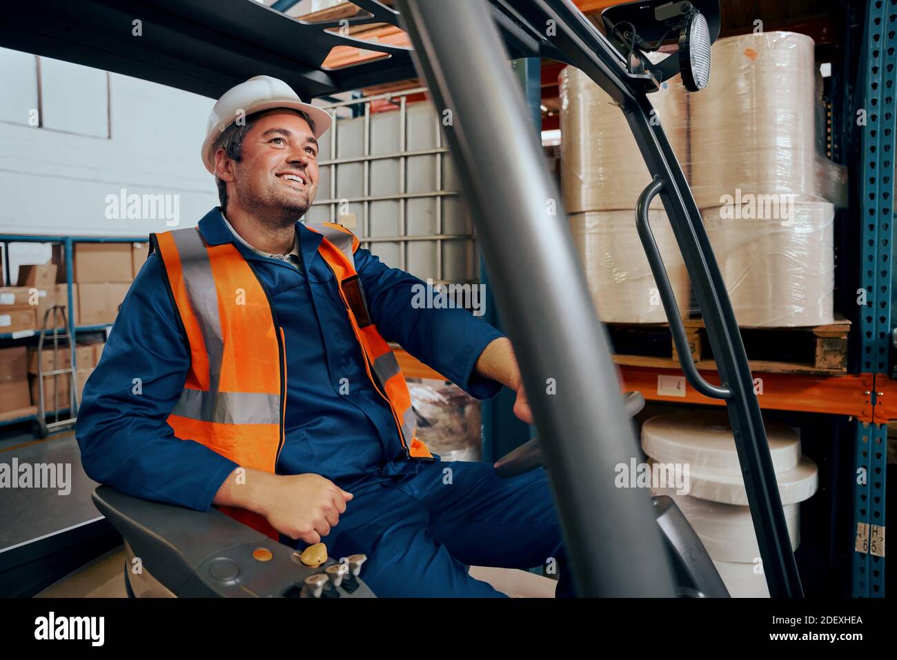 Happy engineer operating forklift truck in warehouse Stock Photo - Alamy