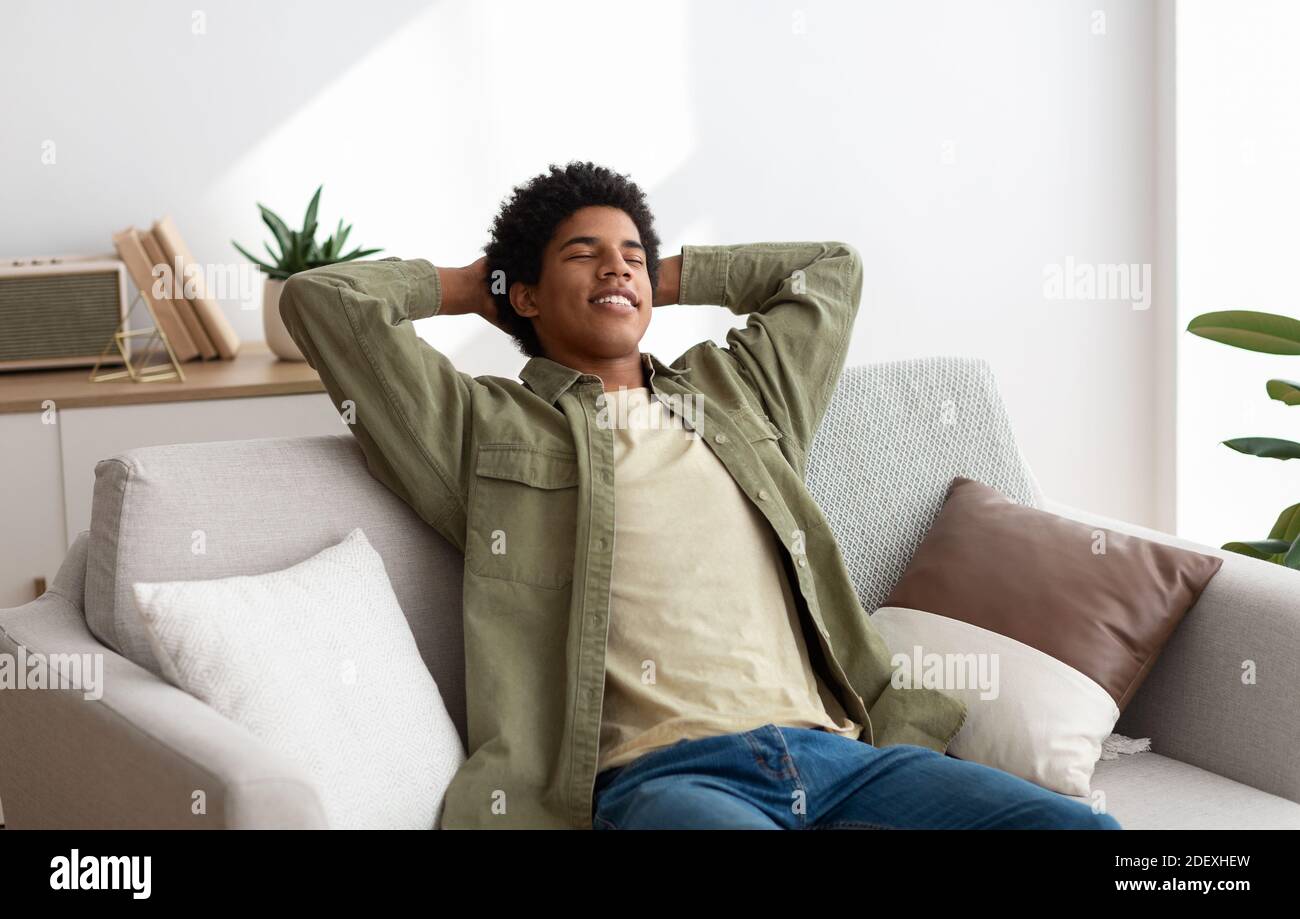 Calm young teen guy relaxing on sofa, napping with closed eyes, feeling ...