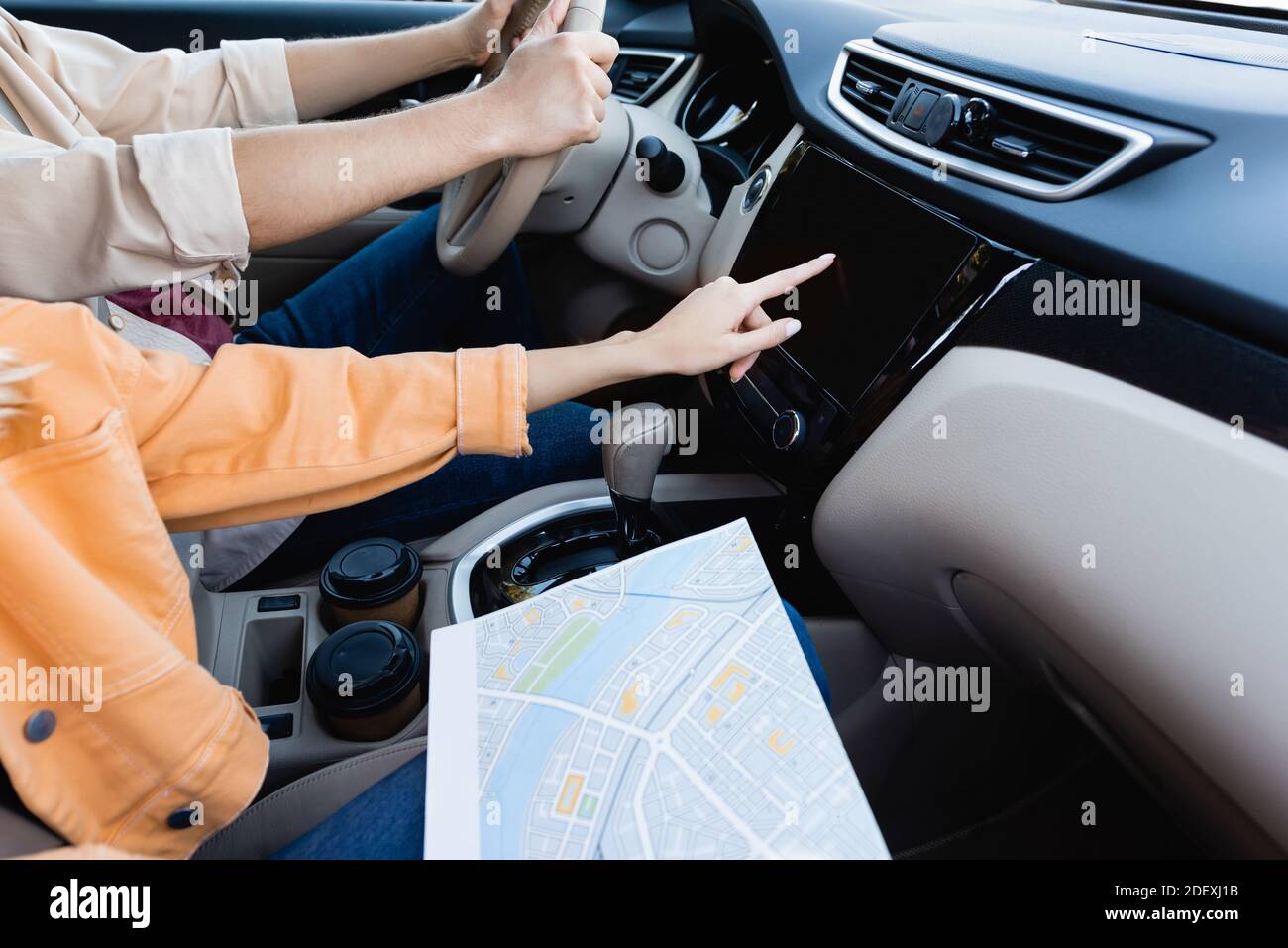 Cropped view of woman with map using audio system while husband driving ...