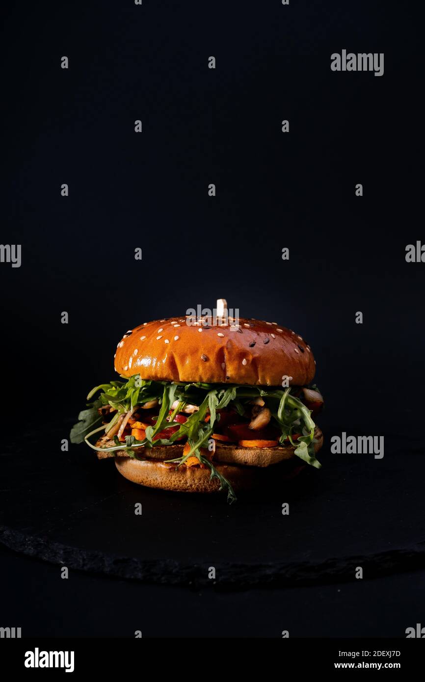 A vertical shot of a delicious burger on a black surface Stock Photo ...