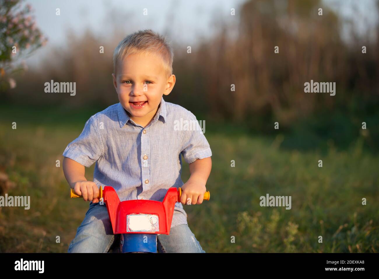 Happy little boy rides a red toy motorcycle Stock Photo - Alamy
