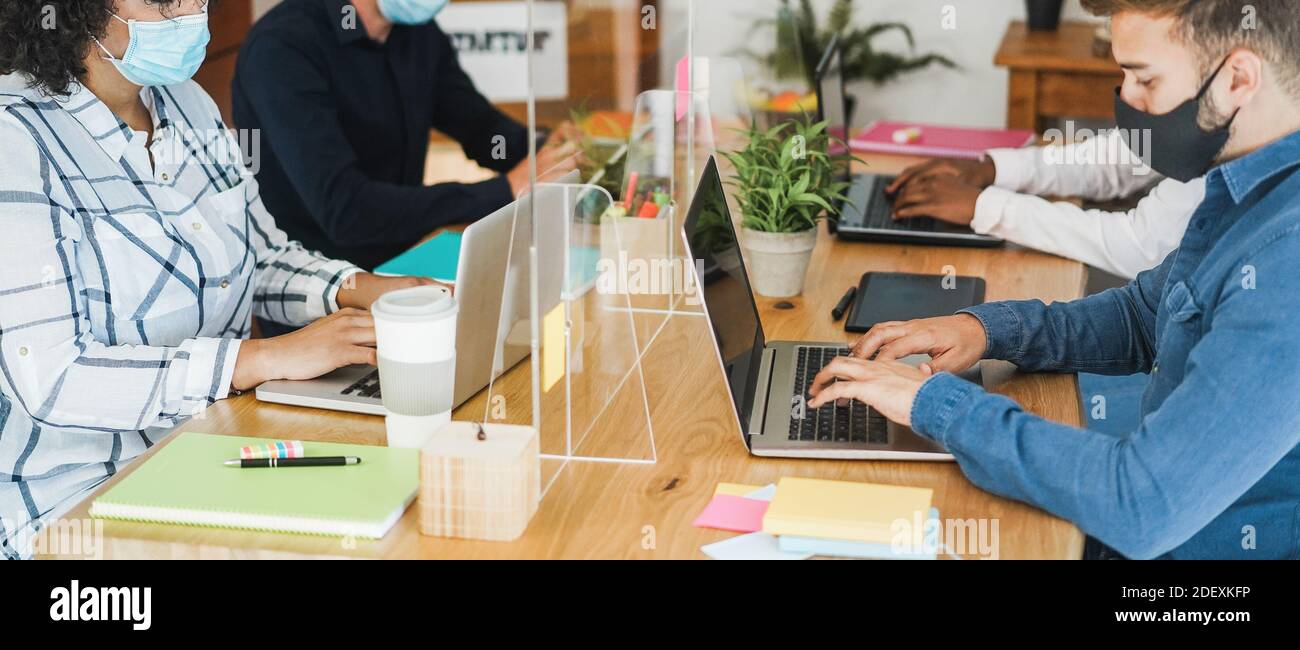 Young people working inside coworking office while wearing protective ...