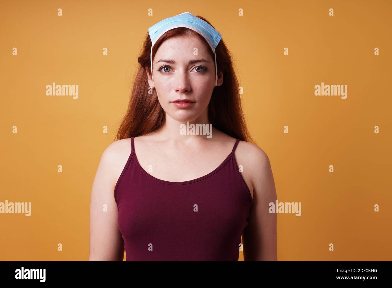 young woman wearing medical face mask wrong on her head using it as ...