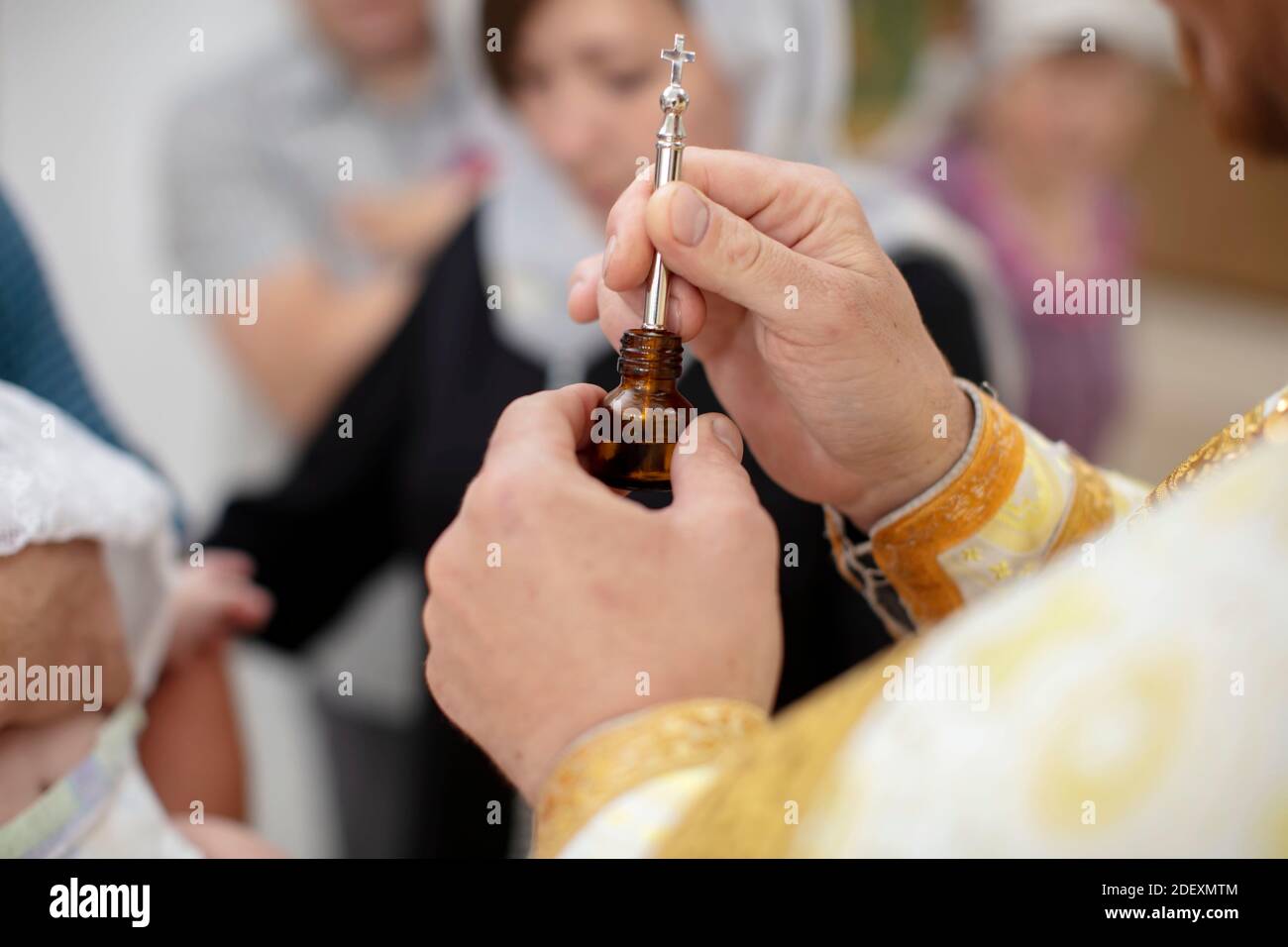 The priest's hands are holding a bottle of incense and a brush for ...