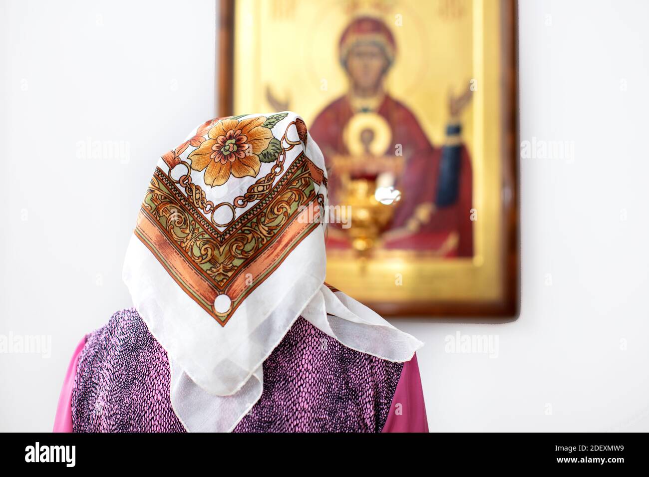 A Russian woman in a headscarf stands facing the icon Stock Photo - Alamy