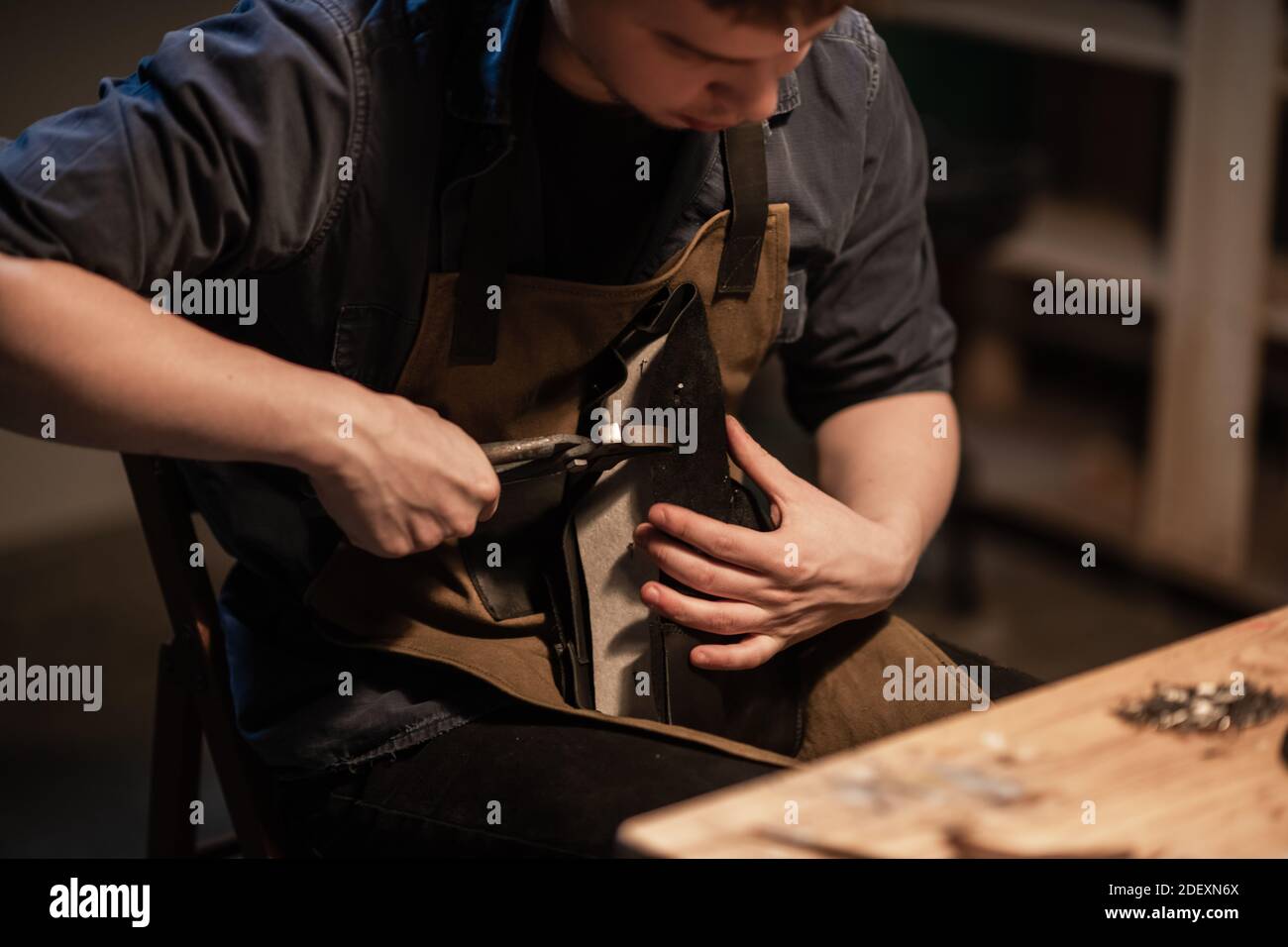 a young talented shoemaker in the workshop is engaged in manual ...