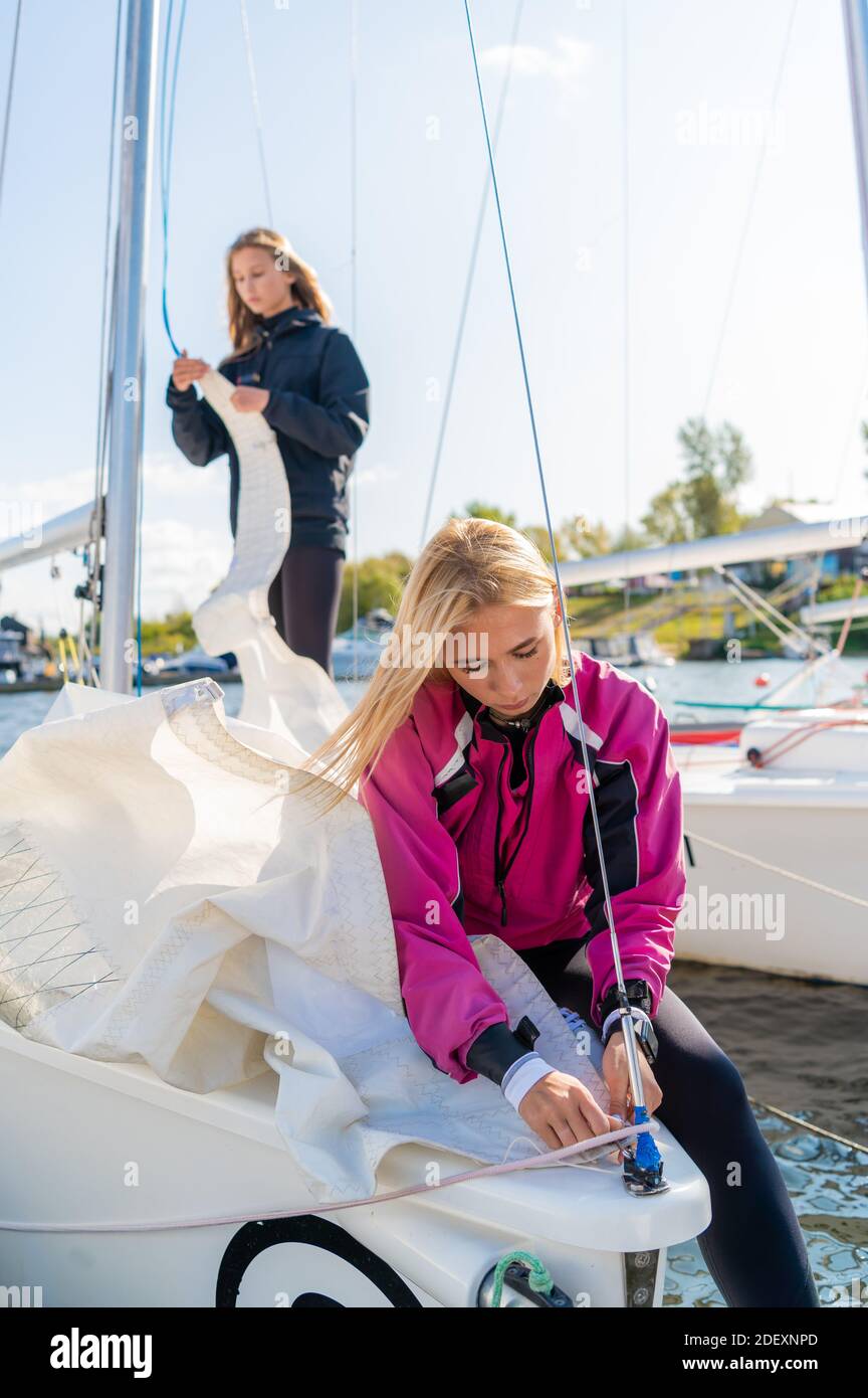 Before the competition on sailing boats two cute girls athletes equip ...