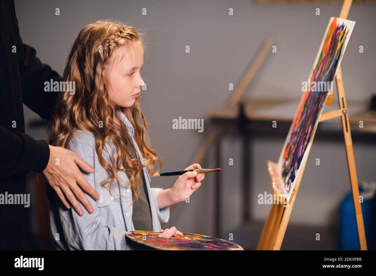 The father supports the daughter in learning to draw. The teacher helps ...