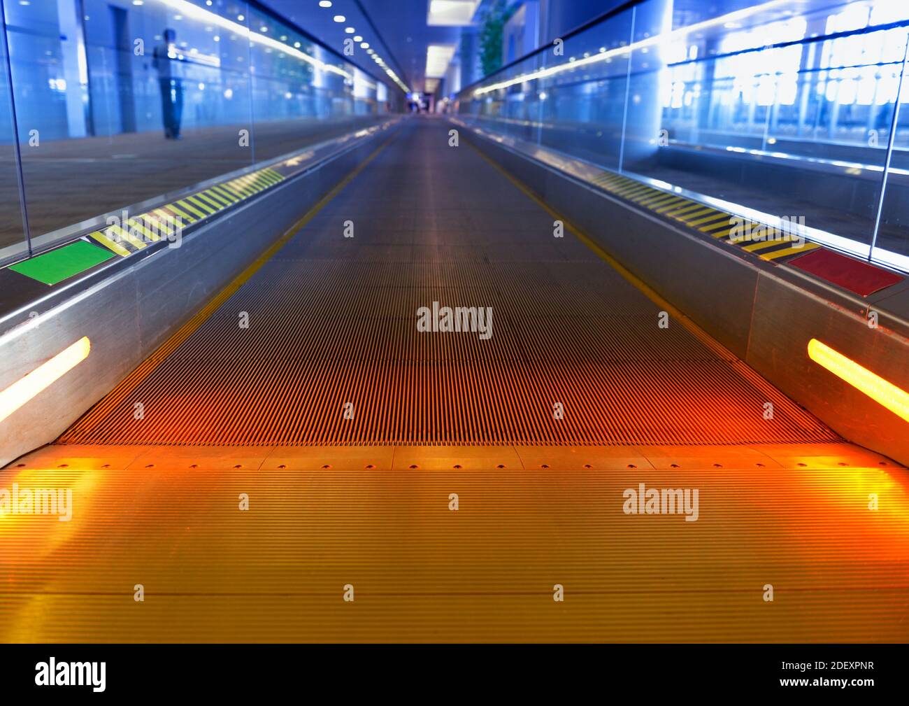Low angle view at long, empty travelator. Mix of natural and neon light ...