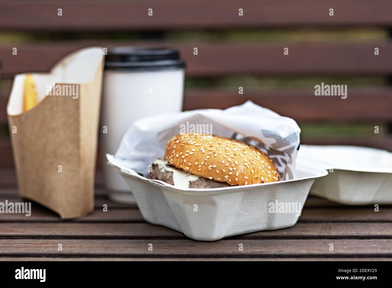 Fast food. Paper cups with coffee, hamburger boxes and fries on a park ...