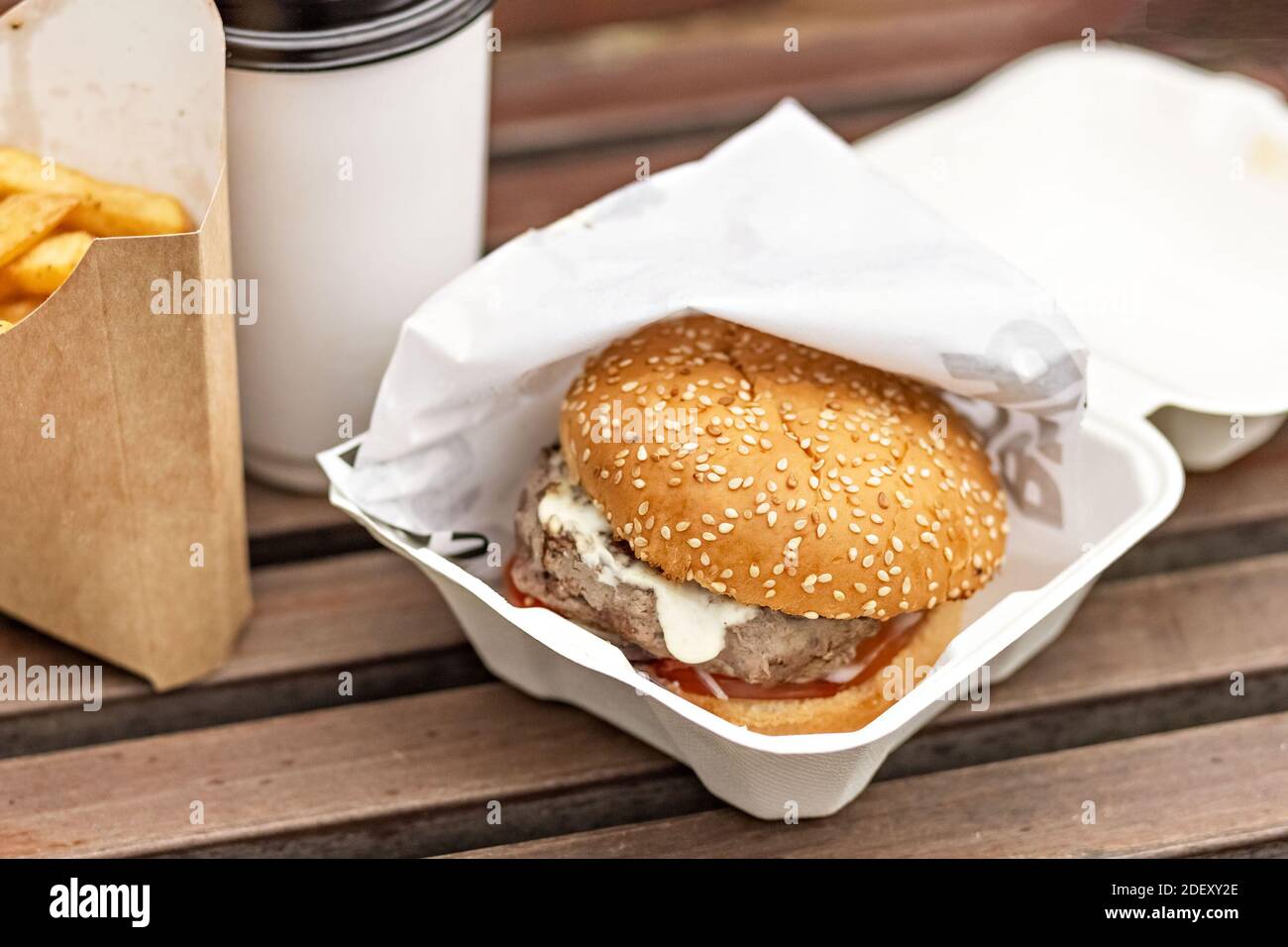 Fast food. Paper cups with coffee, hamburger boxes and fries on a park ...