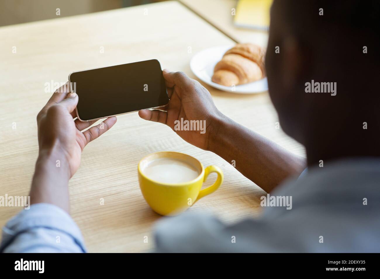 Unrecognizable African American guy holding mobile phone with empty ...