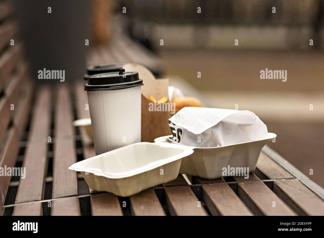 Fast food. Paper cups with coffee, hamburger boxes and fries on a park ...
