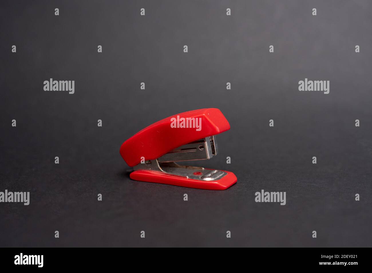 red stapler on a black background Stock Photo - Alamy