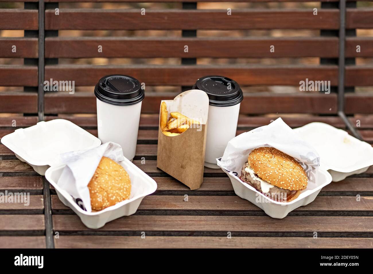 Fast food. Paper cups with coffee, hamburger boxes and fries on a park ...