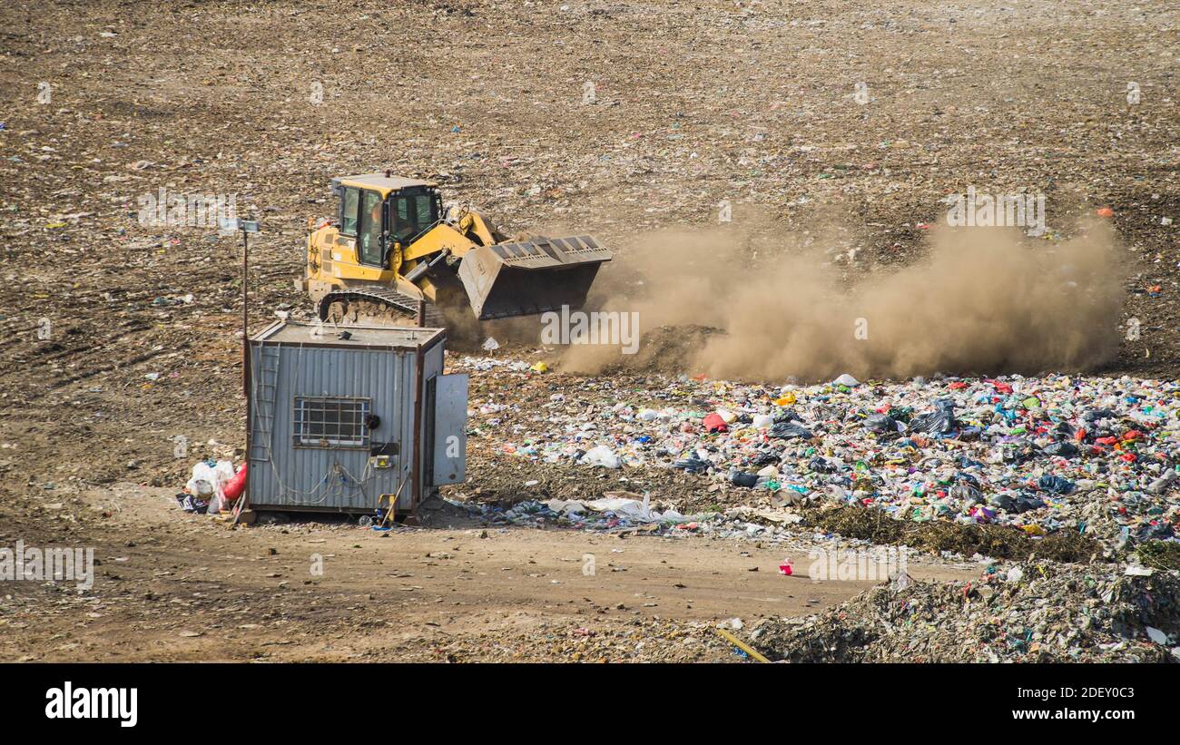 Huge dump of big city near forest. Tractor unloading waste. Preparation ...