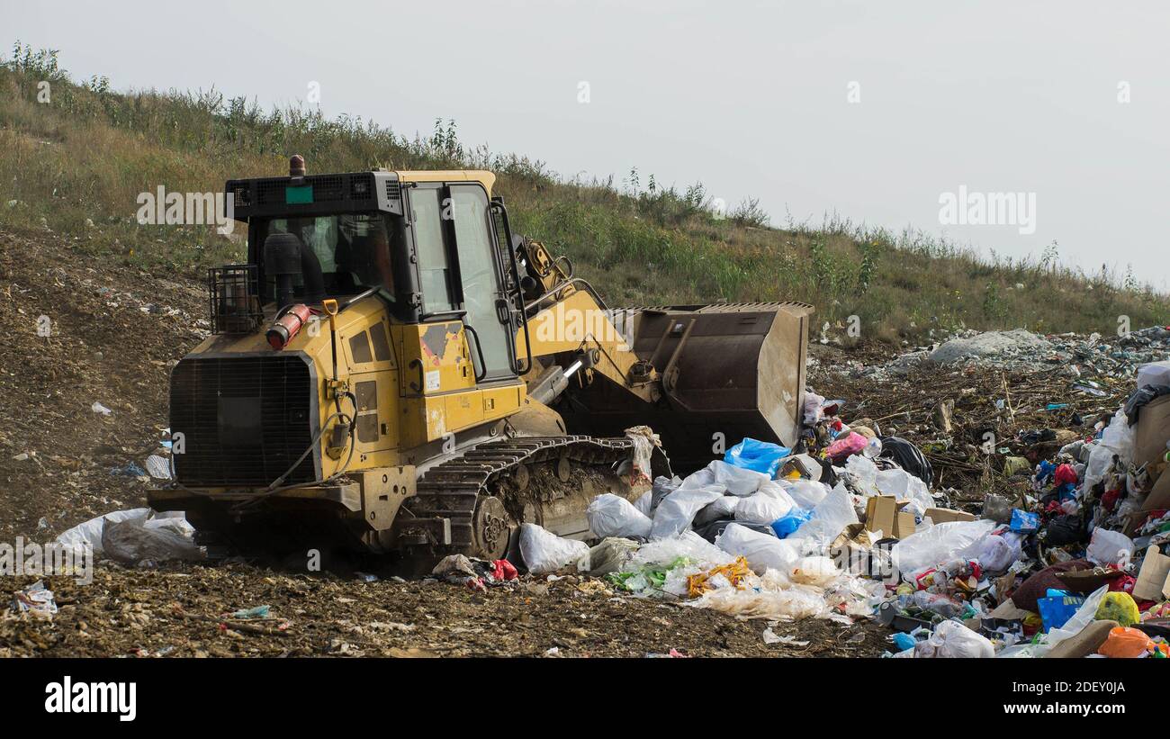 Yellow tractor. Pile of garbage. Waste sorting and preparation for ...