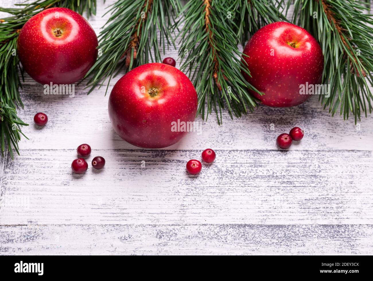 Christmas background with tree branches, red apples and cranberries ...