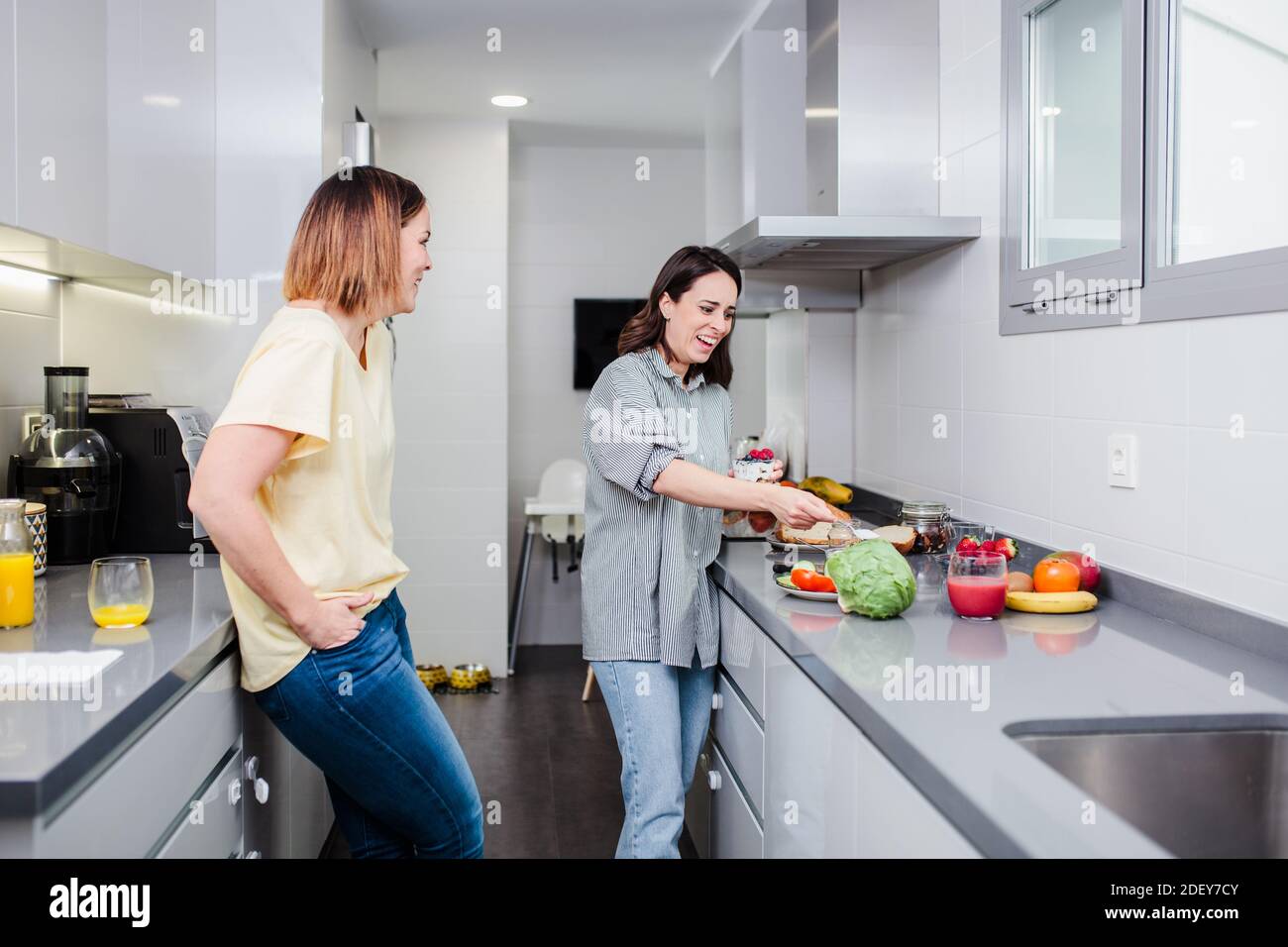 Women preparing healthy food playing with vegetables in kitchen having ...