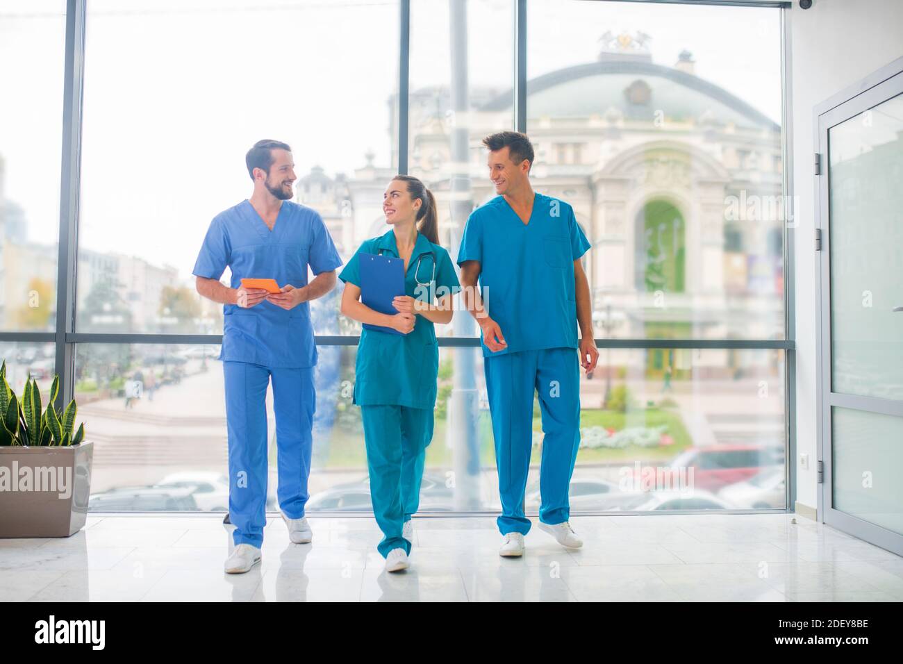 Three doctors walking in the corridor and talking Stock Photo - Alamy