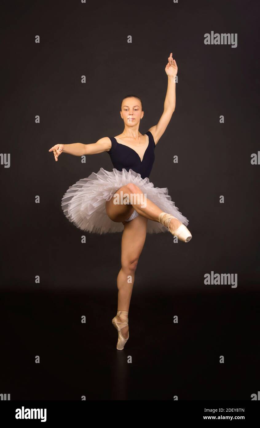 Gorgeous ballerina in a white tutu dancing ballet. Studio shooting on a ...