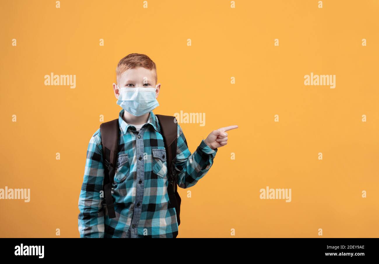 Schoolboy in protective face mask pointing at copy space Stock Photo ...