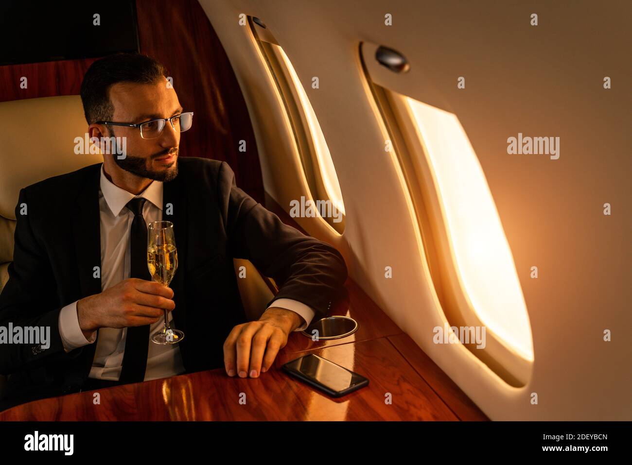 Handsome businessman wearing elegant suit flying on exclusive private ...