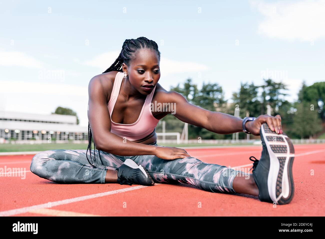 Stock photo of an African-American sprinter stretching her legs before ...