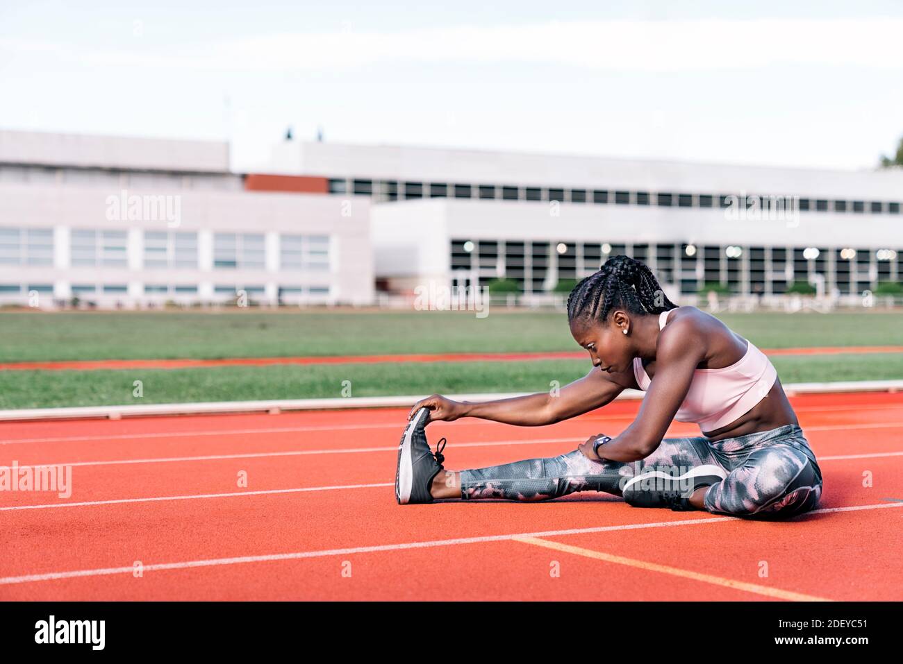 Stock photo of an African-American sprinter stretching her legs before ...