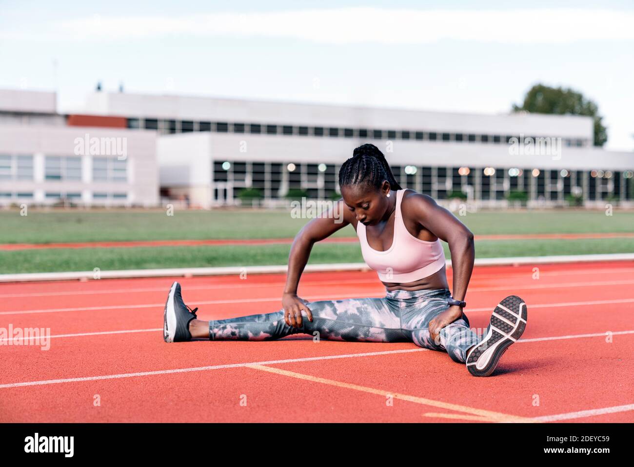Stock photo of an African-American sprinter stretching her legs before ...