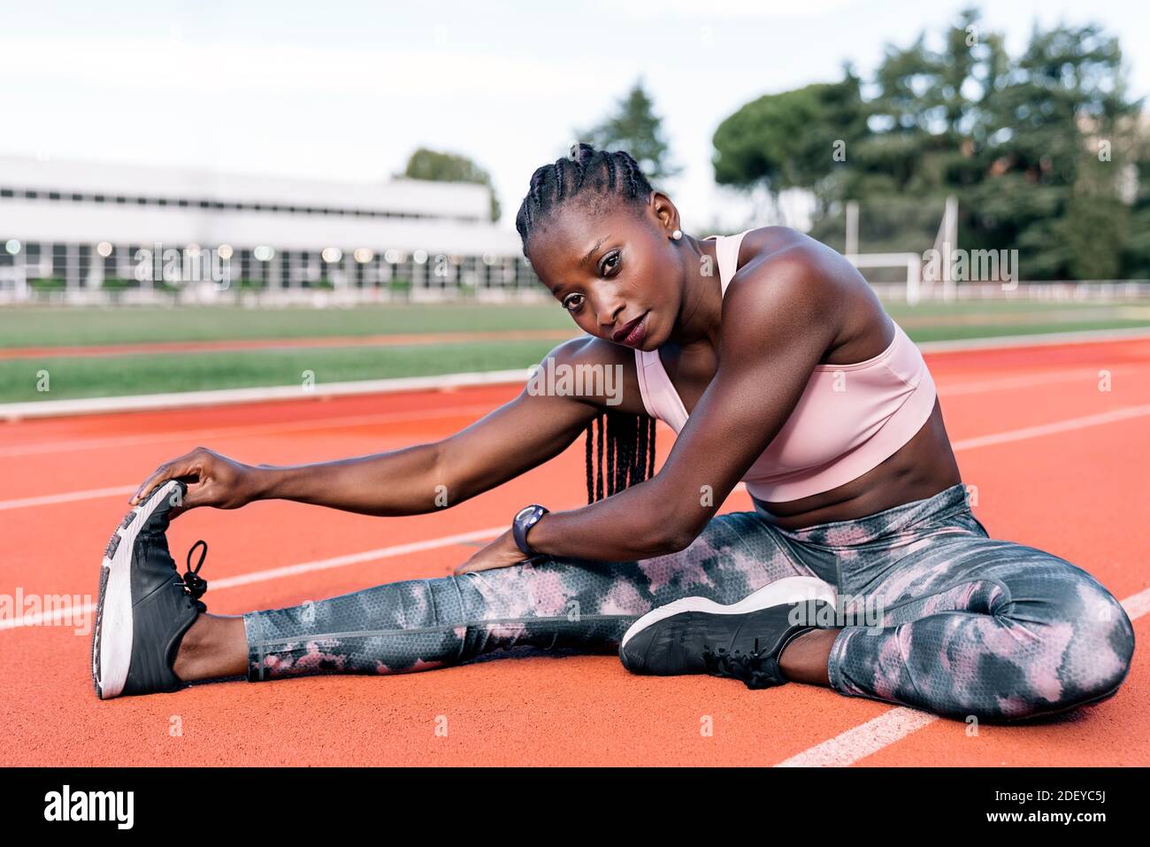Stock photo of an African-American sprinter stretching her legs before ...