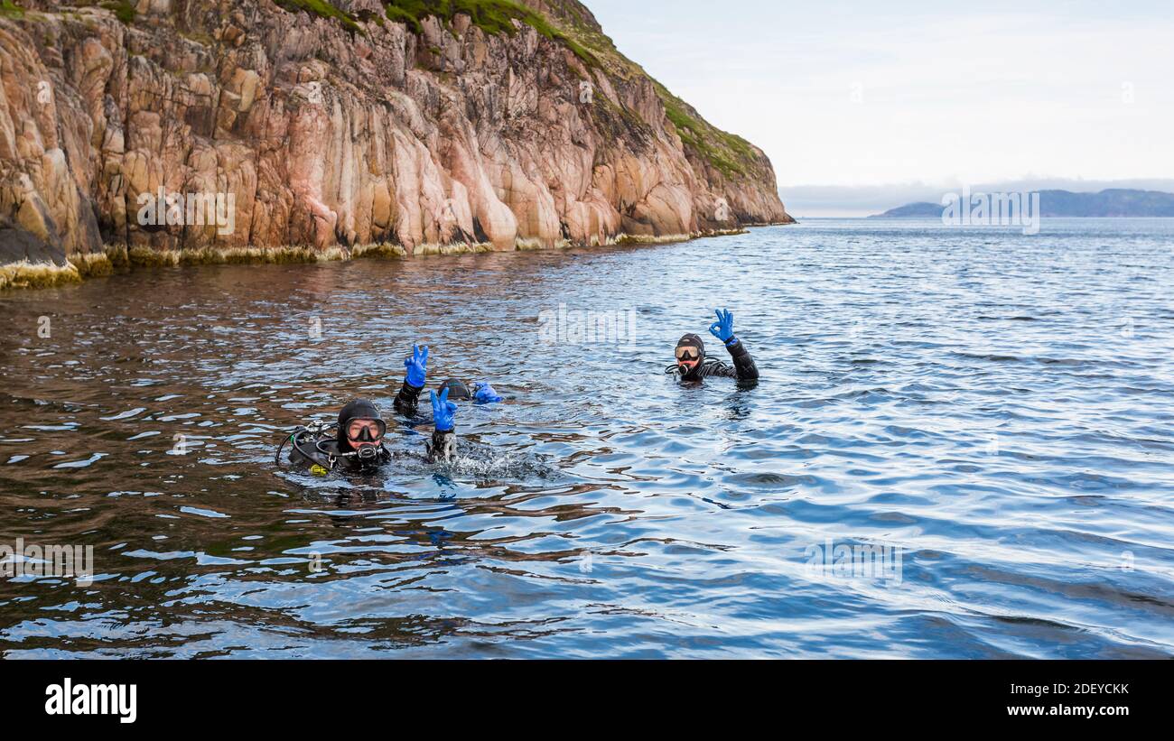 Teriberka, Russia - July 29, 2017: Three scuba divers immersing into ...