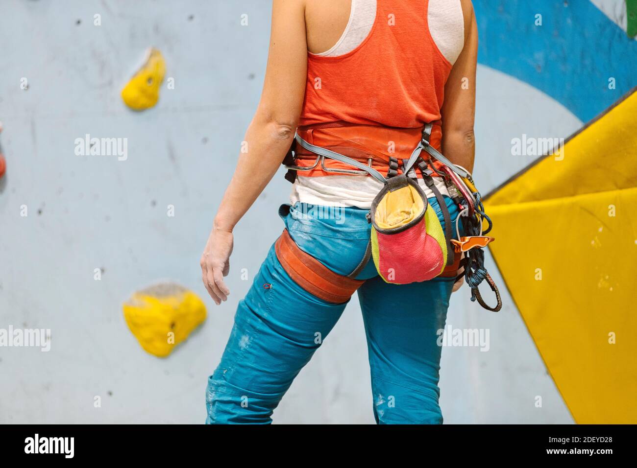 Stock photo of an adult woman standing in front of a rock climbing wall ...