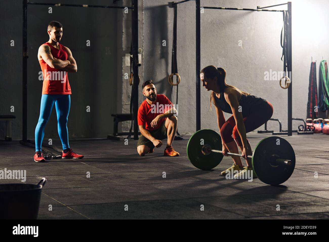 Stock photo of an adult woman in a gym squatting down and lifting a ...