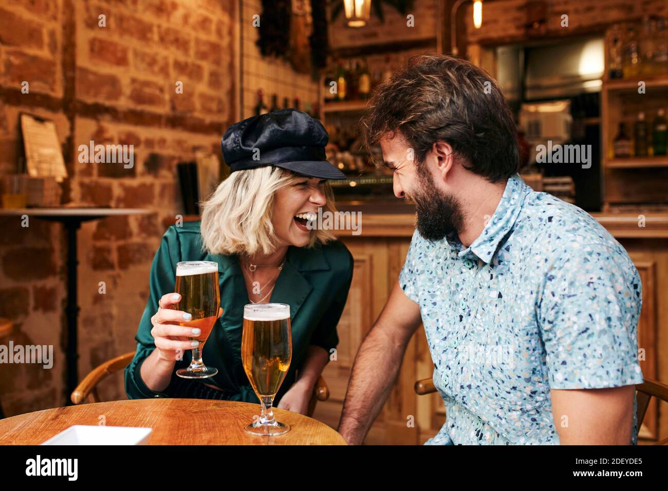 Stock photo of a couple in their 30s having a drink at a bar. They are ...