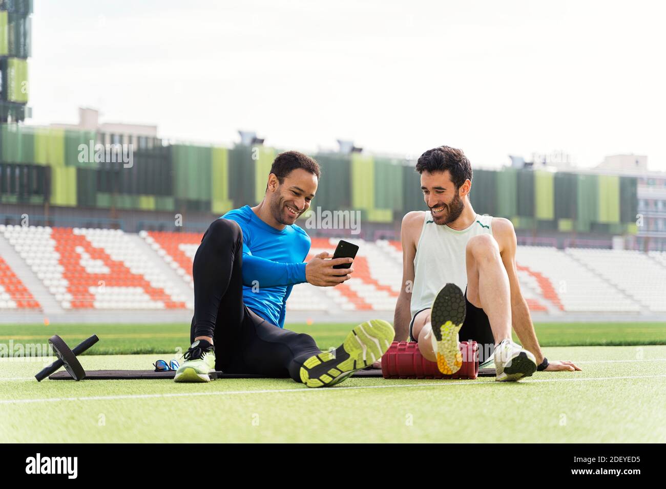 Stock photo of two athlete friends taking a break while using phone in ...