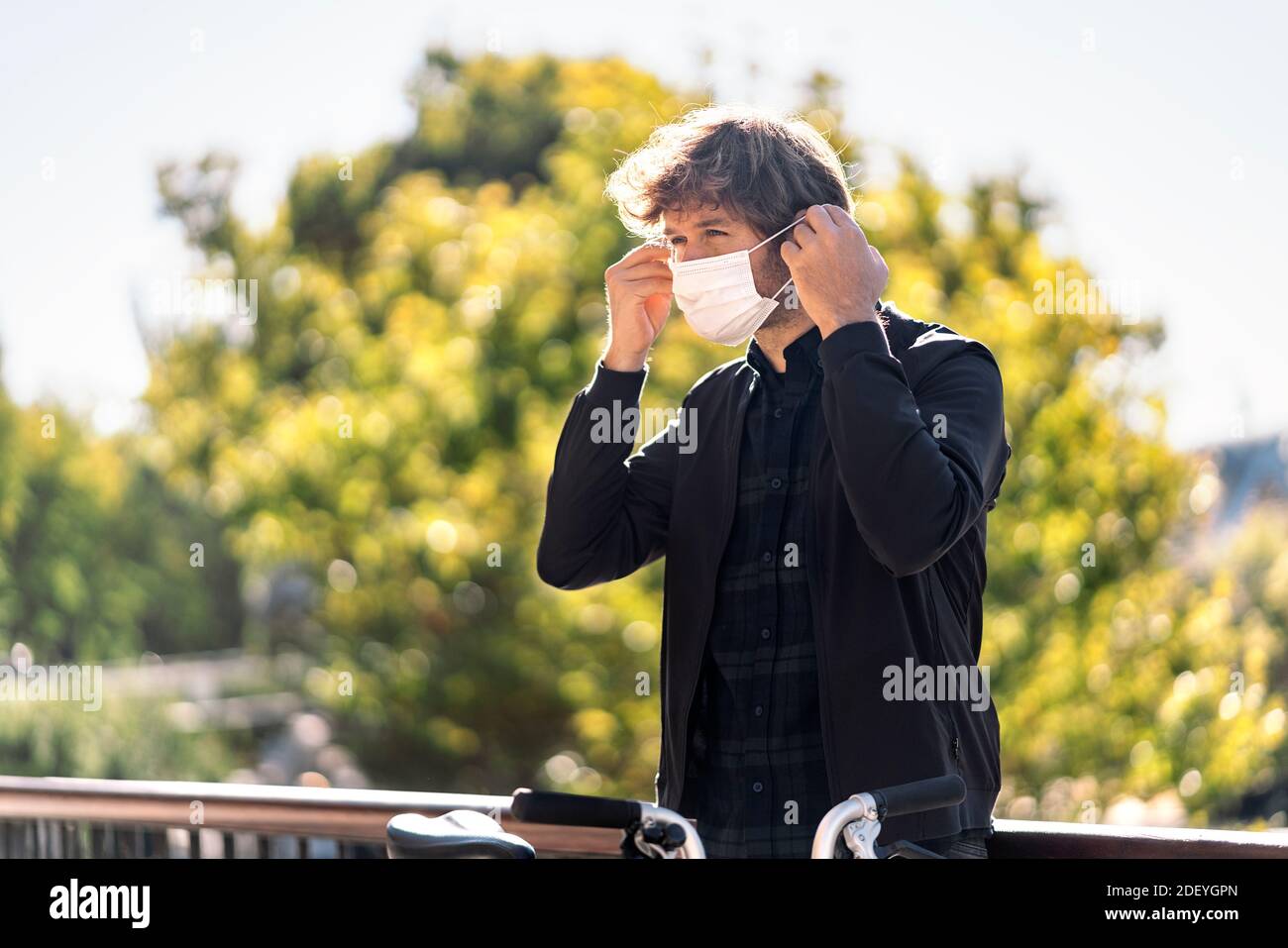 Stock photo of handsome man putting on his face mask in the street ...