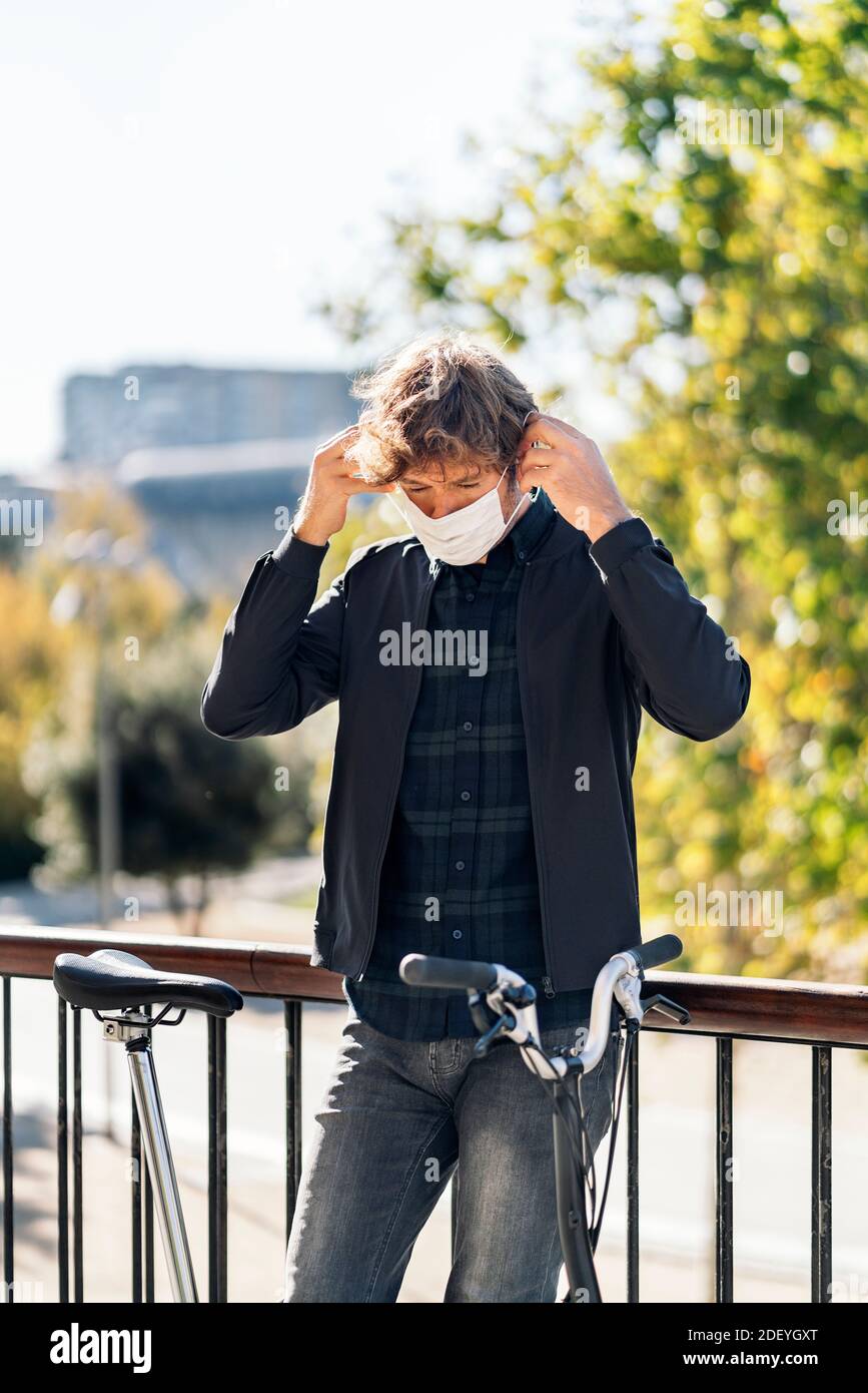 Stock photo of handsome man putting on his face mask in the street ...