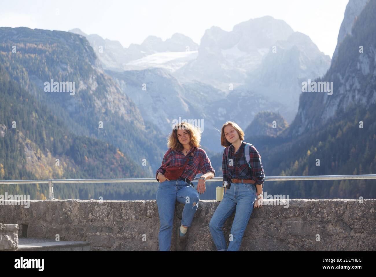 mountain trip. two happy girls on the background of a mountain lake and ...
