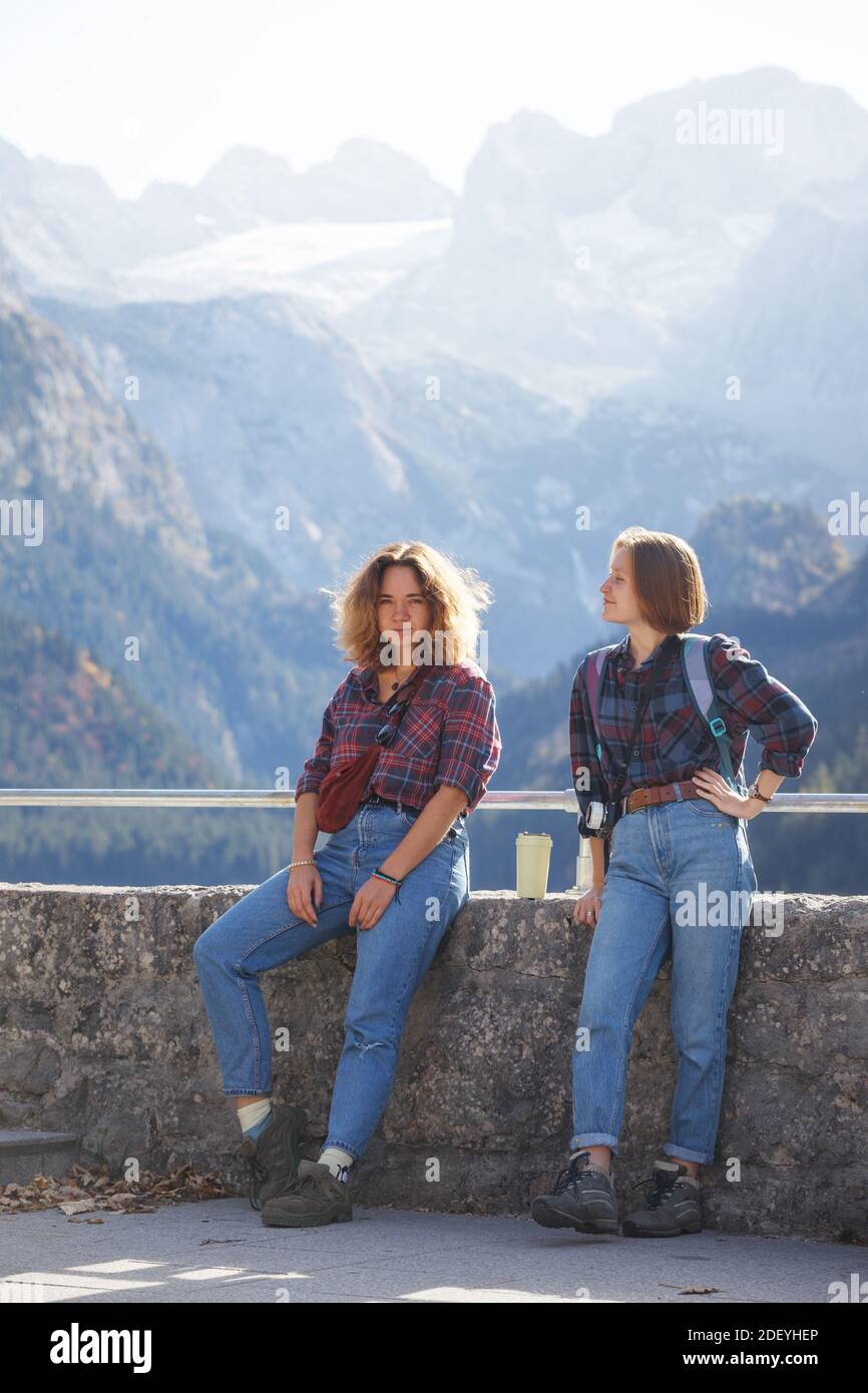 mountain trip. two happy girls on the background of a mountain lake and ...