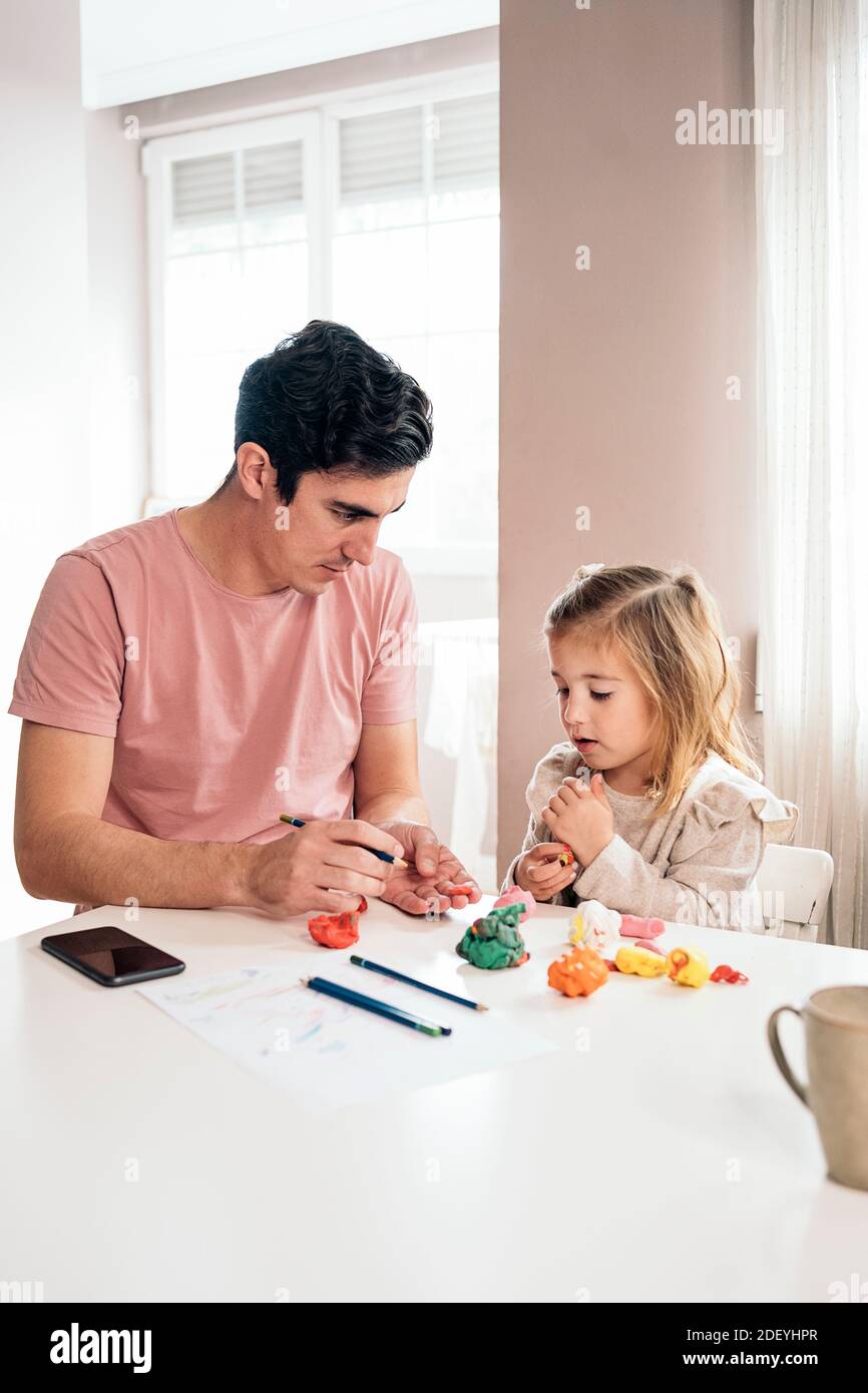 Stock photo of lovely young girl playing with modelling clay at home ...