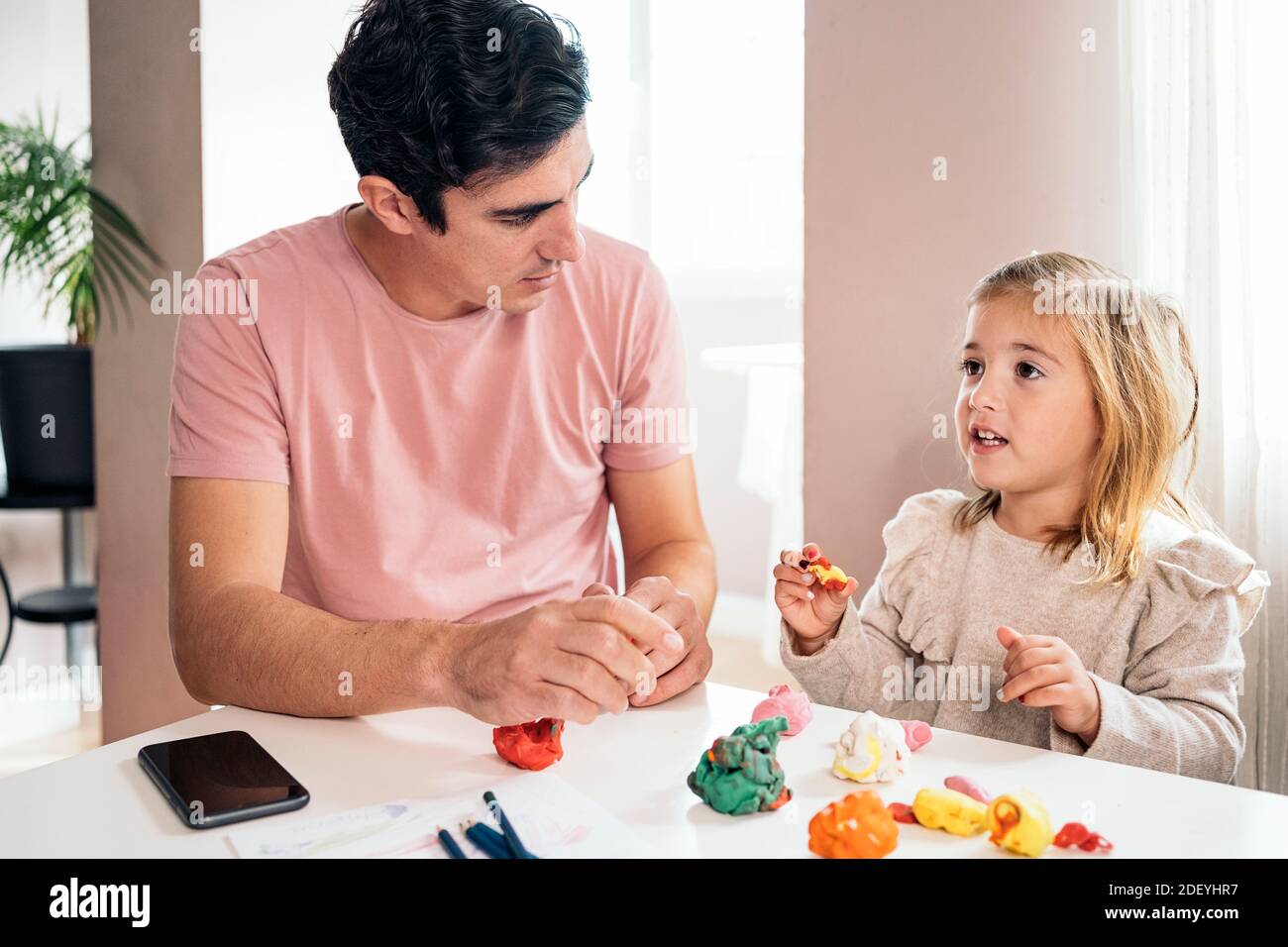 Stock photo of lovely young girl playing with modelling clay at home ...
