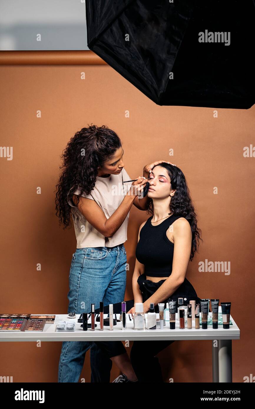 Stock photo of cool makeup artist doing makeup to her client in studio ...