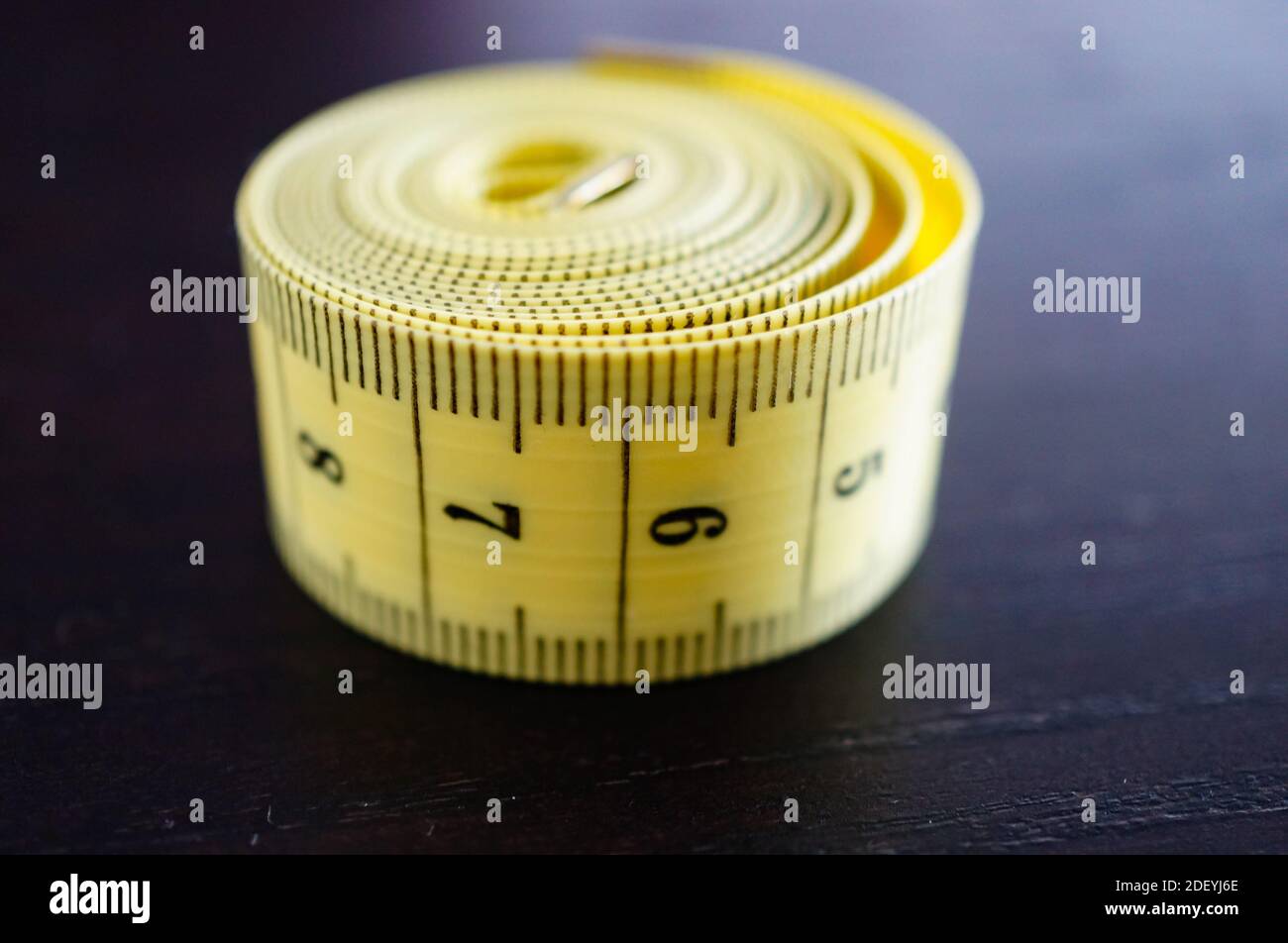 A close up shot of a rolled yellow measuring tape in centimeters on a ...