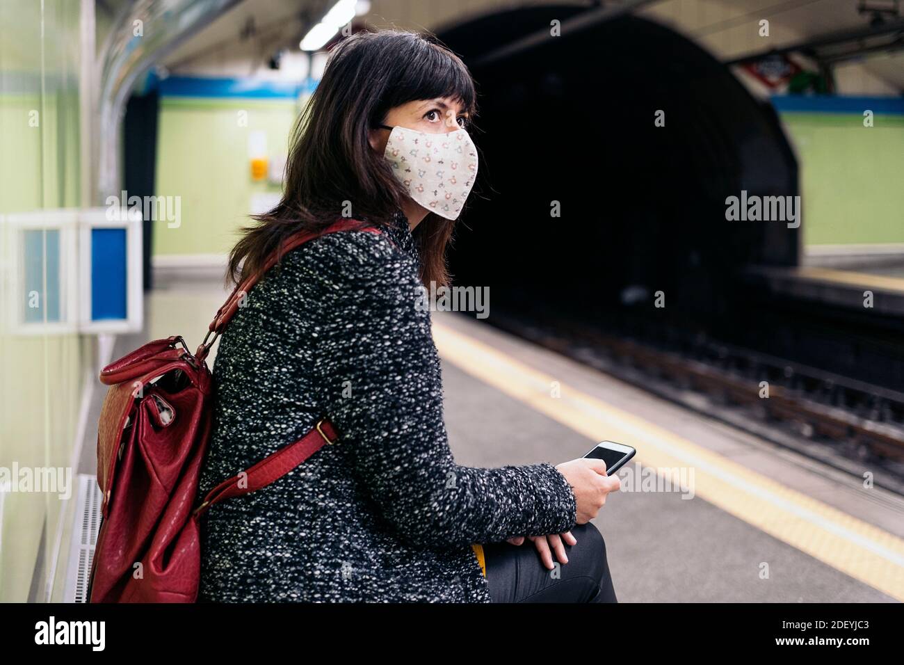 Stock photo of adult woman wearing face mask due to covid19 sitting in ...