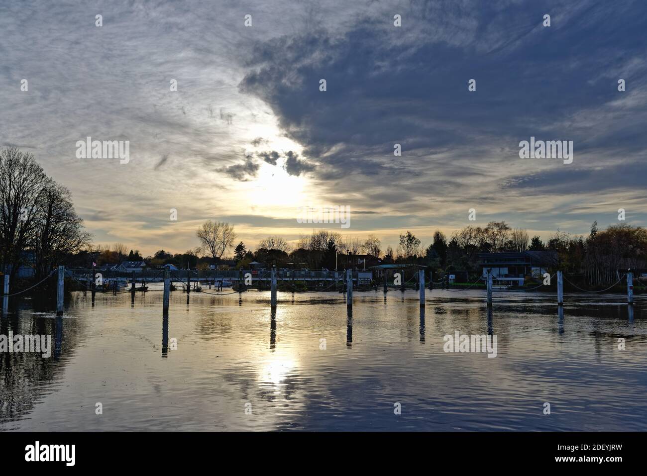 A dramatic winter sunset and dark clouds reflected on the surface of ...