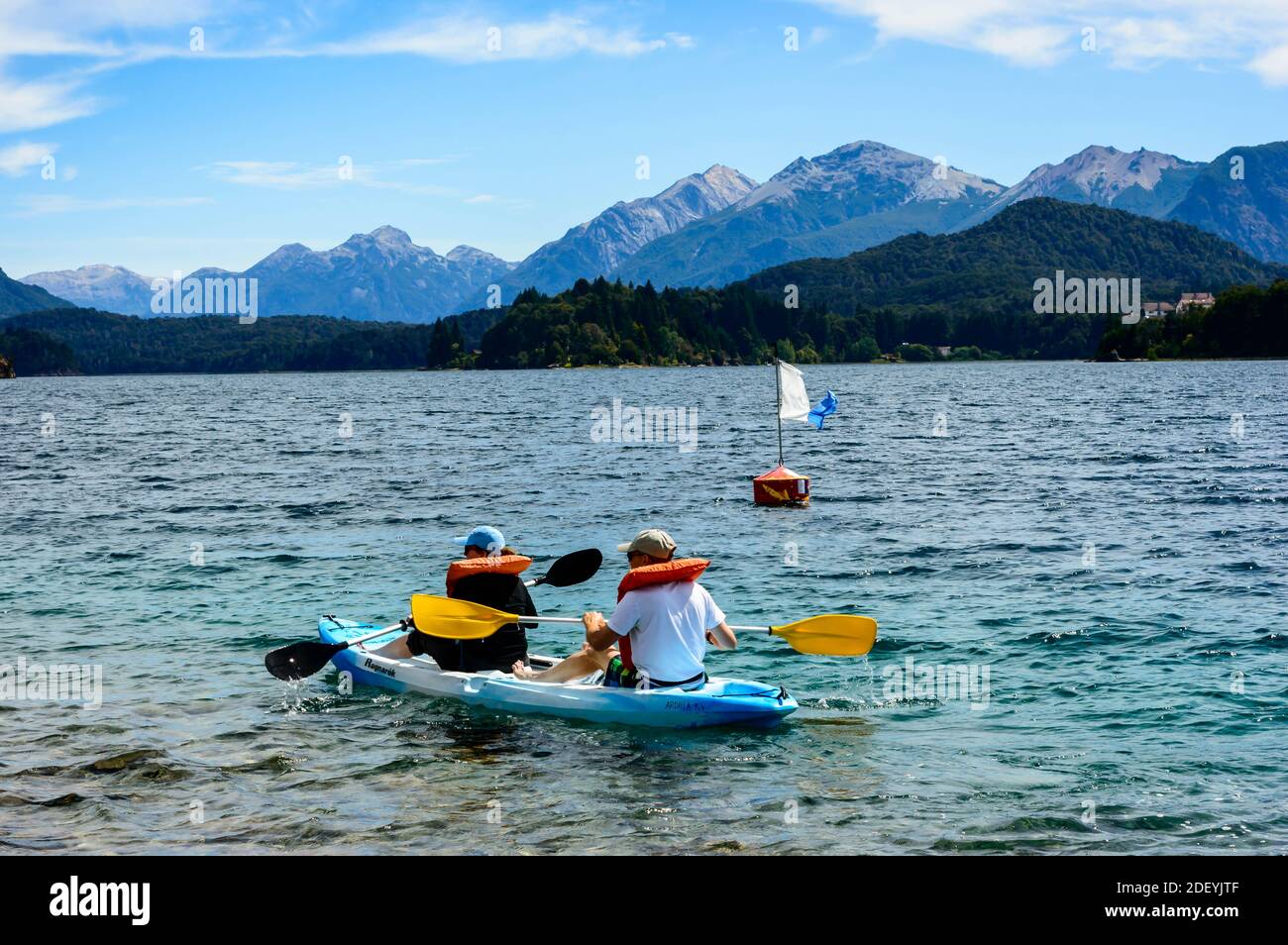 Couple paddling kayak in Lake Bariloche. Summer, rocks, pines and ...